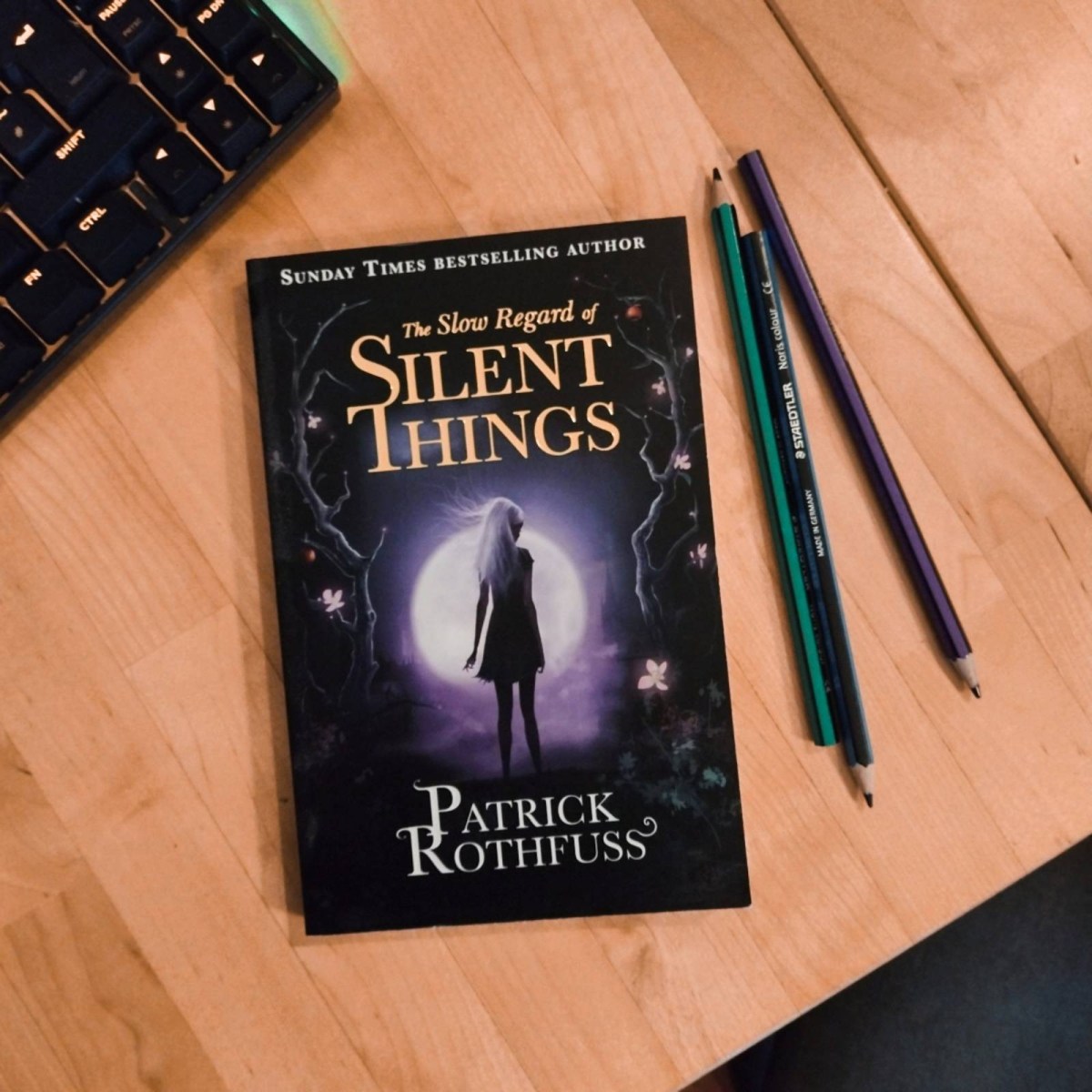 “The Slow Regard of Silent Things” by Patrick Rothfuss – em with pen